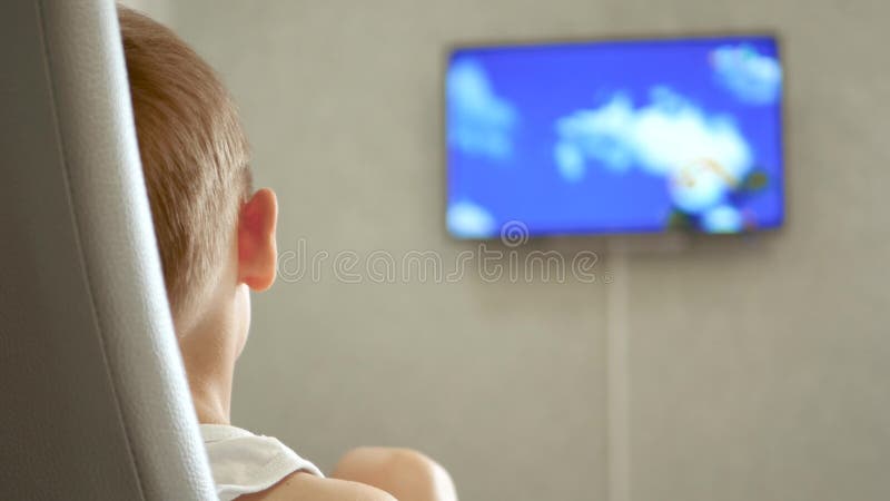 A Child is Watching a Cartoon Sitting on a Chair. the TV Screen is Out ...