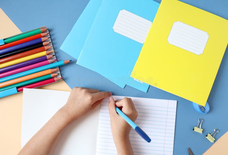 A Child Writes with a Pen in a Student`s Notebook on a Table with ...