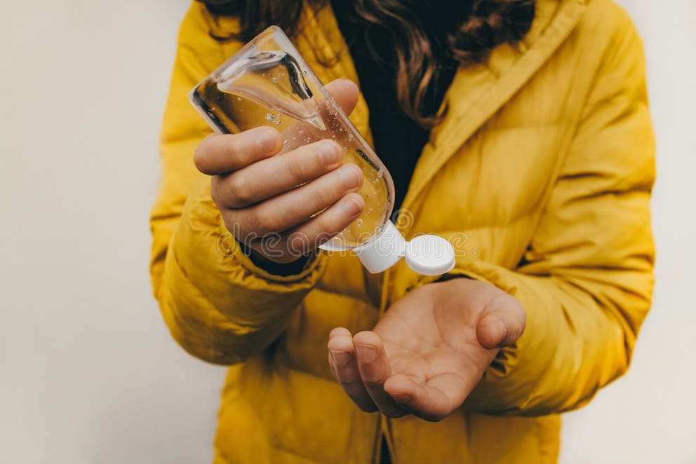 A Child in a Yellow Jacket. in Hands a Bottle with Gel for Processing ...