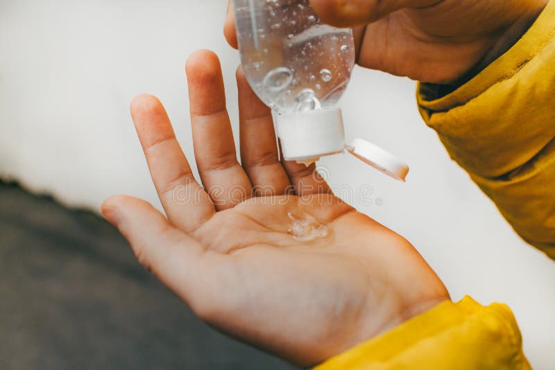 A Child in a Yellow Jacket. in Hands a Bottle with Gel for Processing ...