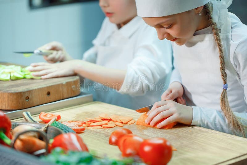 Children in Chef`s Hat Grind Vegetables on the Kitchen. Stock Image ...