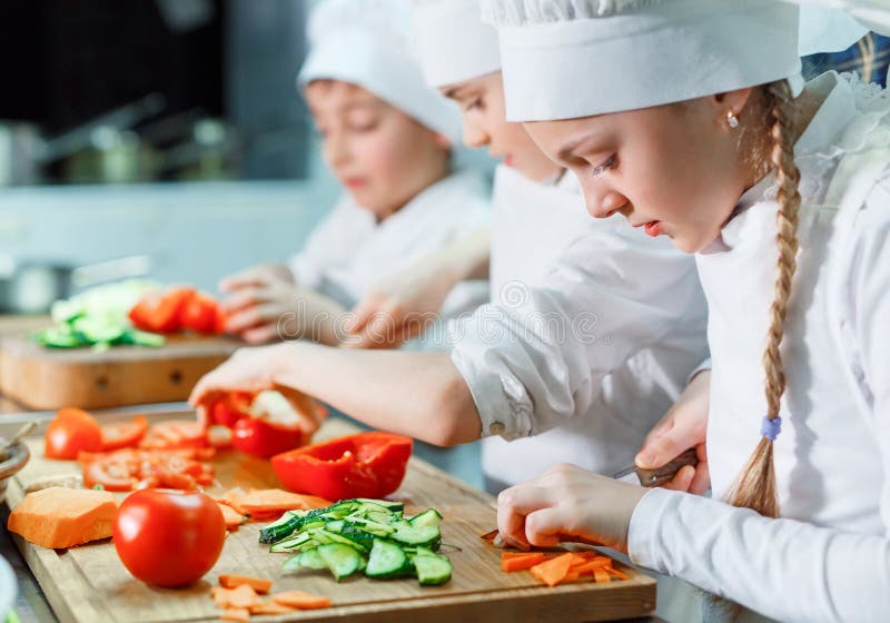 Children in Chef`s Hat Grind Vegetables on the Kitchen. Stock Image ...