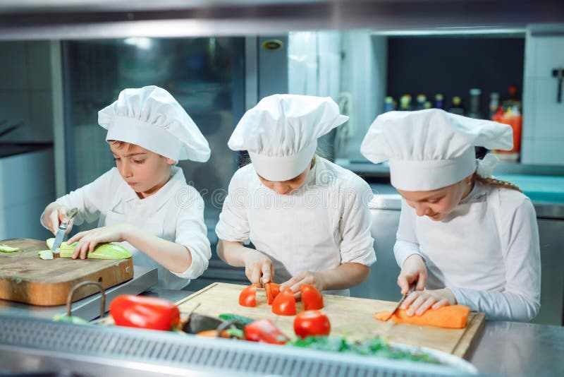 Children in Chef`s Hat Grind Vegetables on the Kitchen. Stock Photo ...