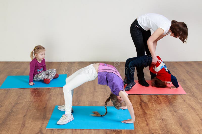 Children are Doing a Bridge Exercise with the Help of a Trainer Stock ...