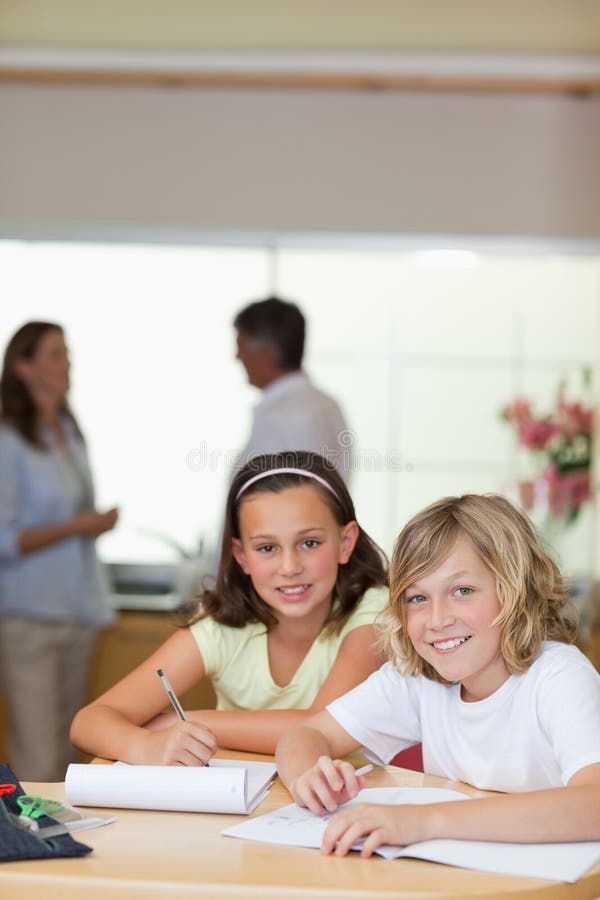 Children Doing Homework with Their Parents Behind Them Stock Photo ...
