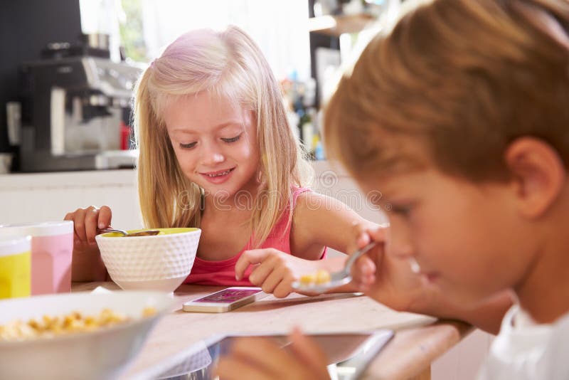 Children Eating Breakfast Whilst Playing with Mobile Phone Stock Image ...
