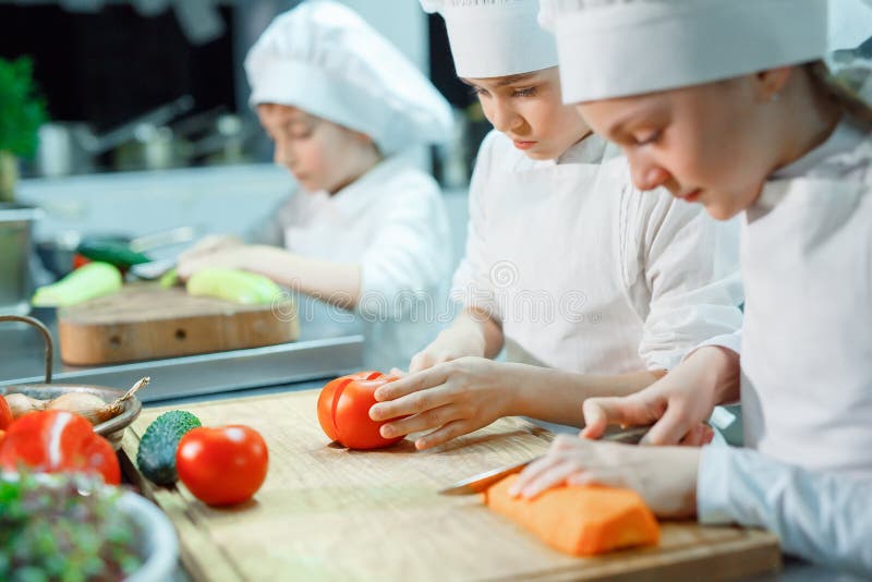 Children in Chef`s Hat Grind Vegetables on the Kitchen. Stock Image ...