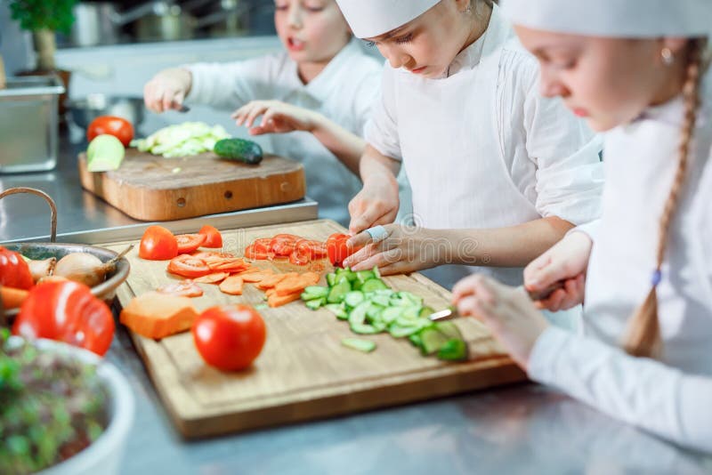 Children in Chef`s Hat Grind Vegetables on the Kitchen. Stock Image ...