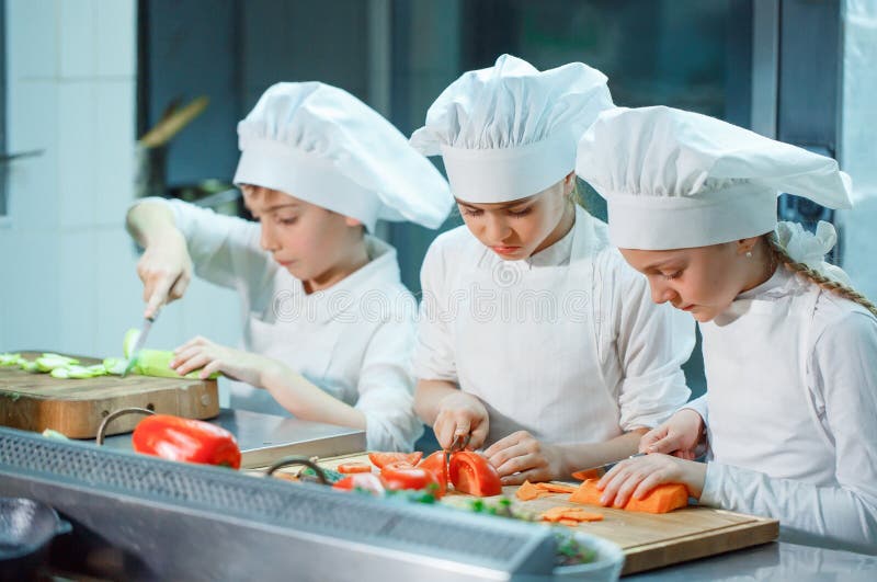 Children in Chef`s Hat Grind Vegetables on the Kitchen. Stock Image ...