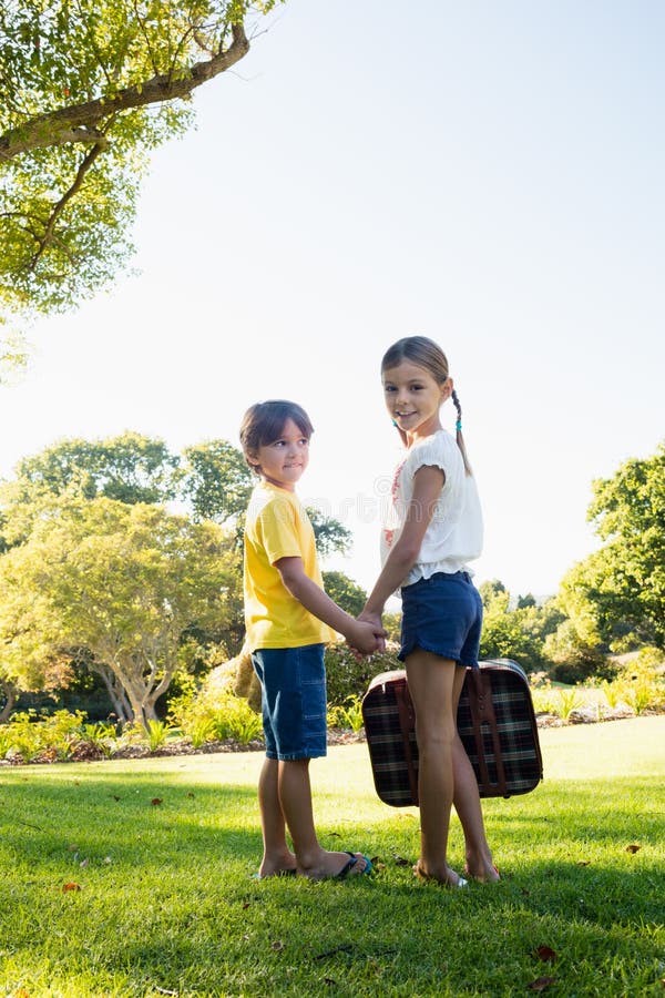 Children Holding Their Hands Looking Back while Holding a Luggage Stock ...