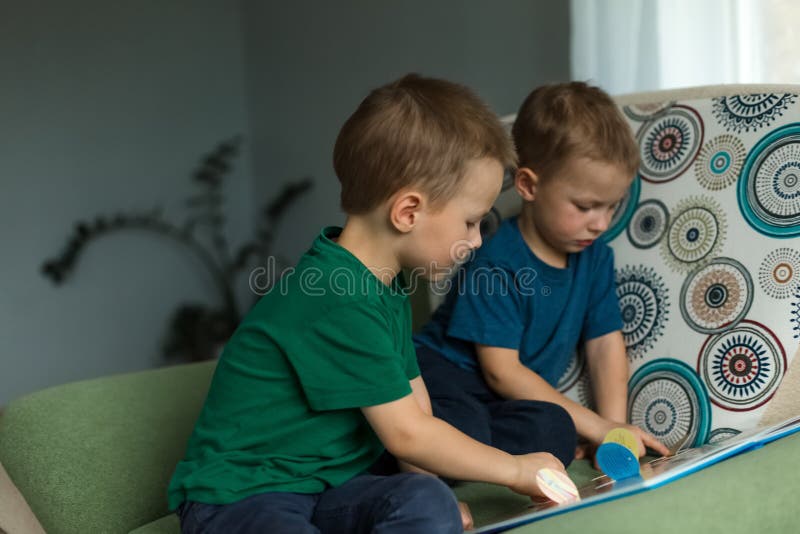 Children at Home Look at a Book on the Sofa Stock Photo - Image of ...