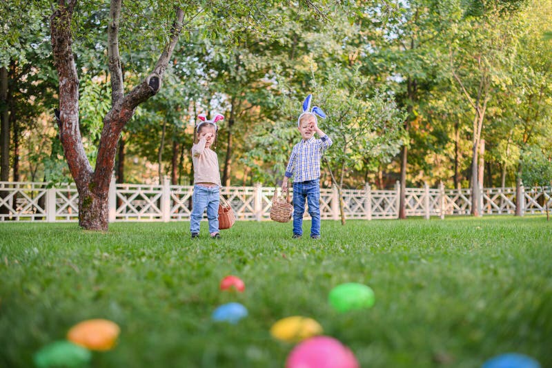Children Hunting Easter Eggs in the Garden with Bunny Ears Stock Photo ...