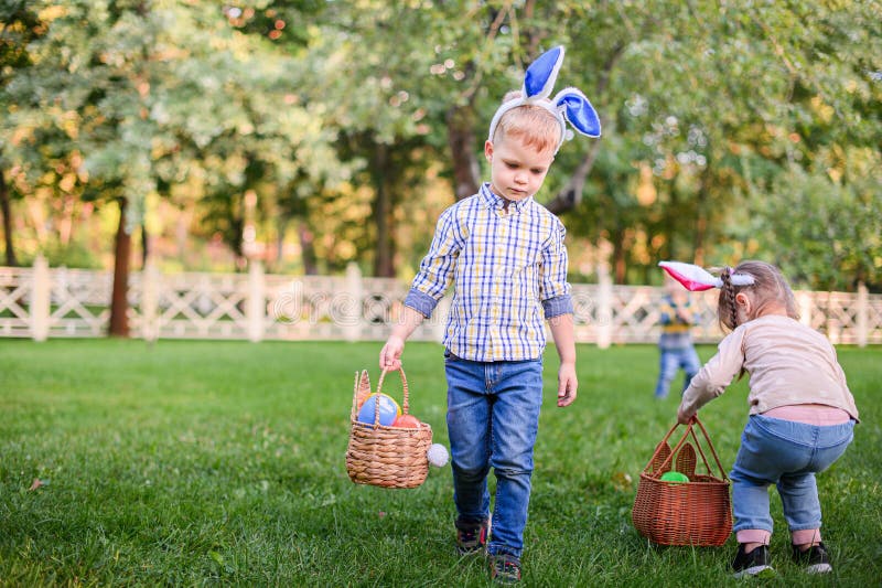 Children Hunting Easter Eggs in the Garden with Bunny Ears Stock Photo ...
