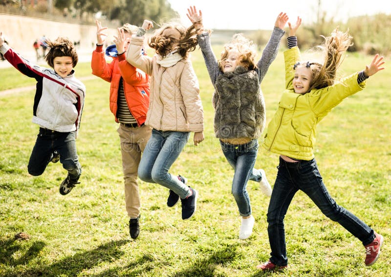Children Jump Up on Lawn in Park Stock Image - Image of colored, motion ...