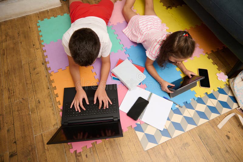 Children Learning on Digital Devices at Home on Colorful Mats Stock ...