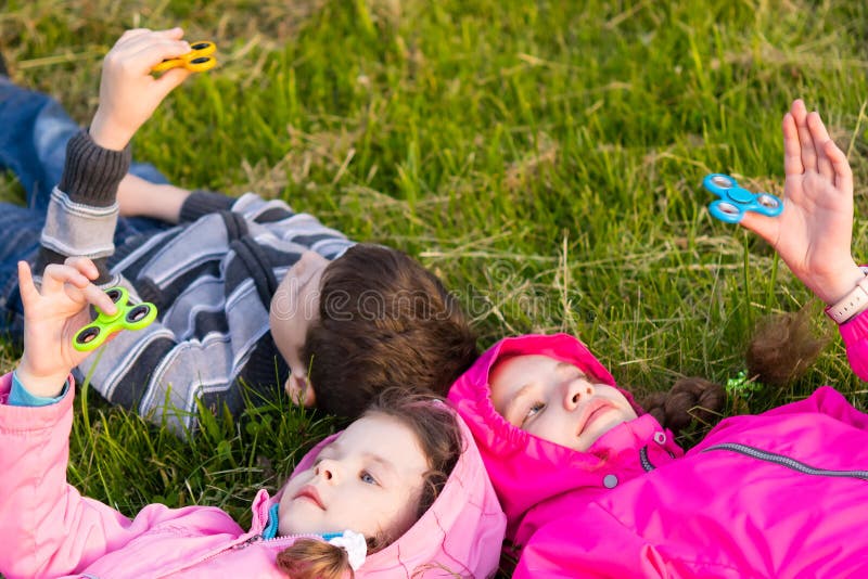 Children Lie on the Grass and Play in the Spinner Stock Image - Image ...