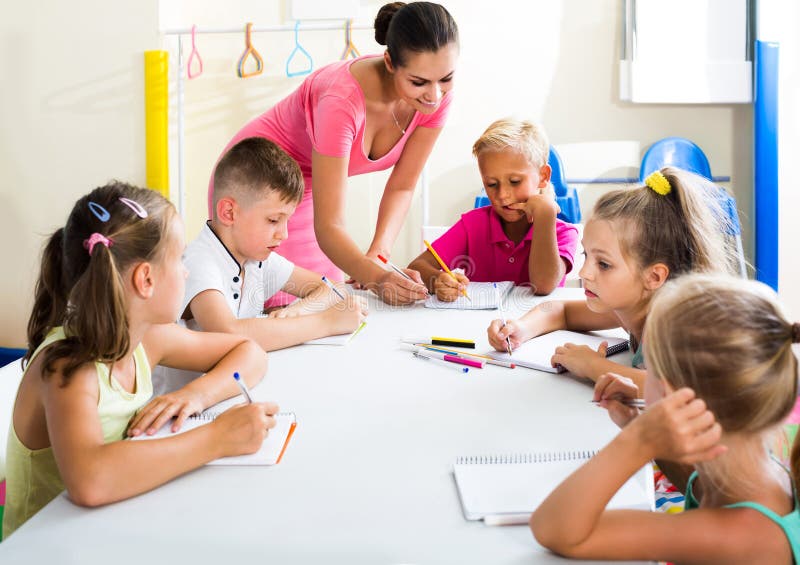 Children Making Writing Exercises with Help of Teacher in Class Stock ...