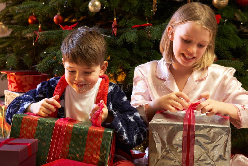 Family Opening Christmas Present in Front of Tree Stock Image - Image ...