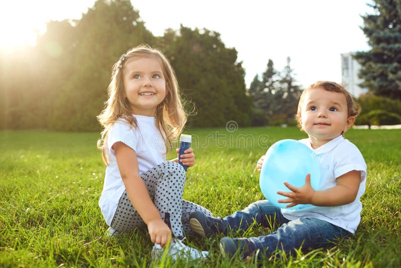 Children Playing on the Grass in the Park at Sunset in the Park. Stock ...
