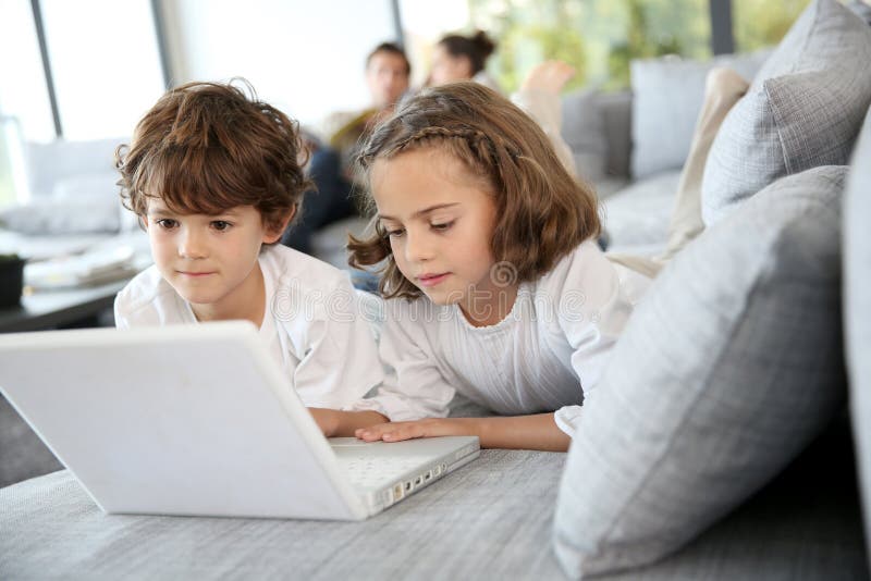 Children Playing with Laptop, Parents in the Back Stock Photo - Image ...