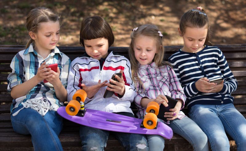 Children Playing with the Phone on Bench Outdoors Stock Image - Image ...