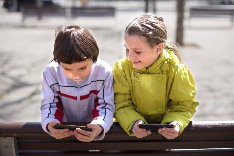 Children Playing on Smartphones on Bench Stock Photo - Image of child ...