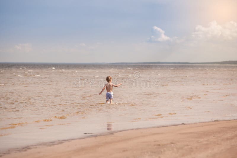 Children Run Along the Beach and Splatters with Water Stock Photo ...