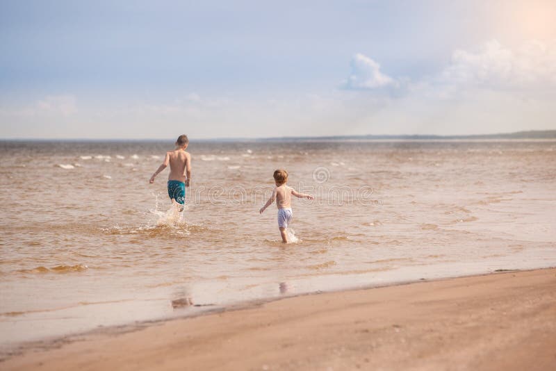 Children Run Along the Beach and Splatters with Water Stock Photo ...