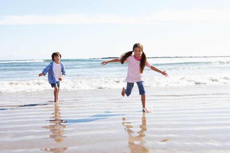 Children Running Away from Breaking Waves on Beach Stock Photo - Image ...