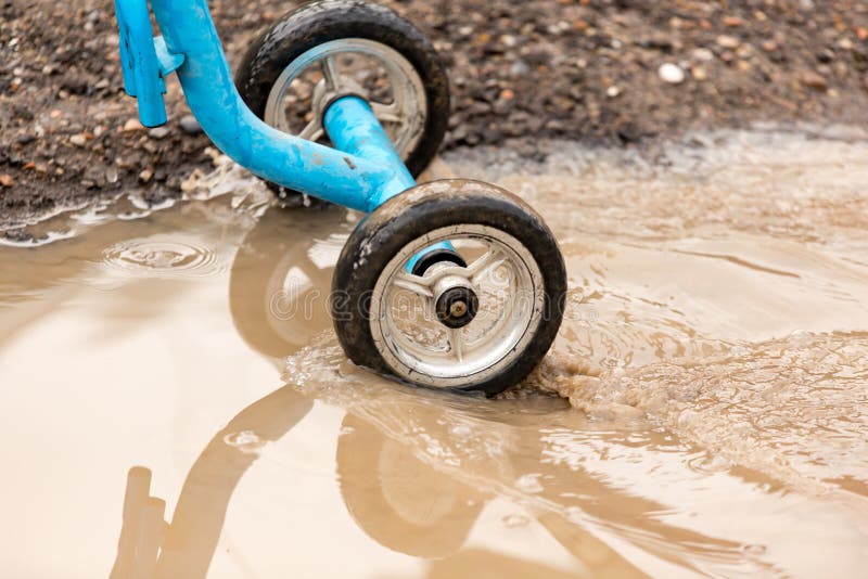 Children`s Bicycle Wheels in a Puddle on the Road Stock Photo - Image ...
