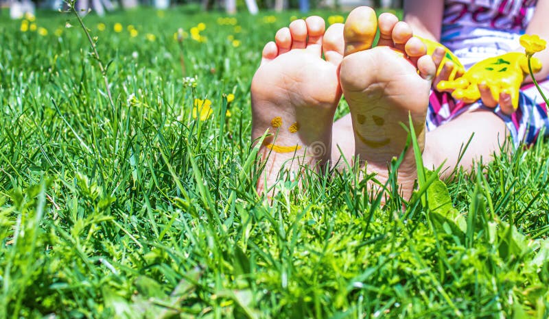 Children`s Feet with a Pattern of Paints Smile on the Green Grass ...