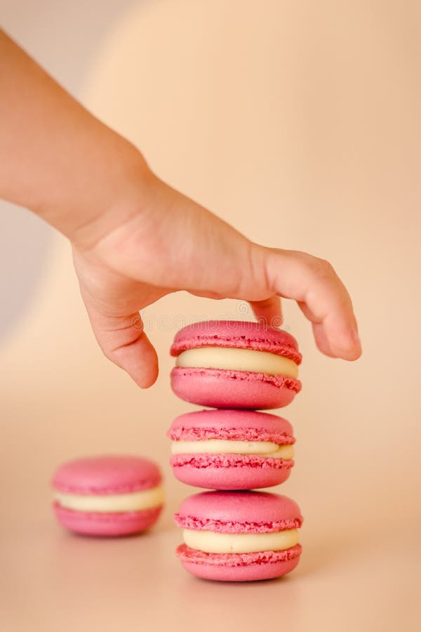 Children`s Hand Reaches for Sweets Pink Macaroons with Cream Stock ...