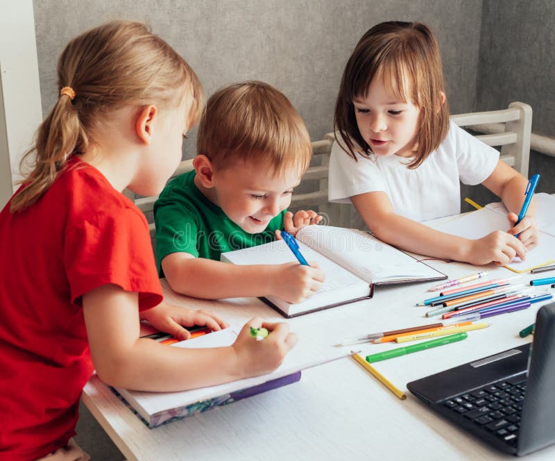 Children Sit at a Table with Pens and Notebooks and Use a Laptop Stock ...