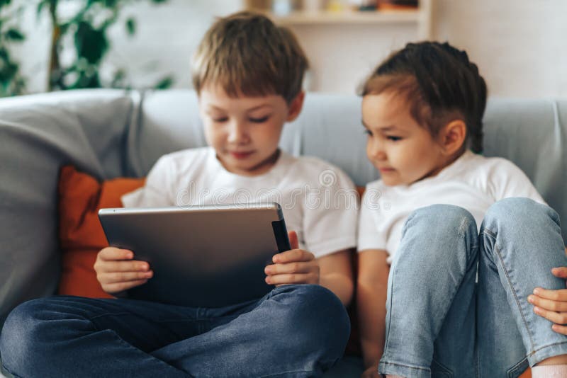 Children Sitting on the Couch Watching Videos on the Tablet Stock Image ...