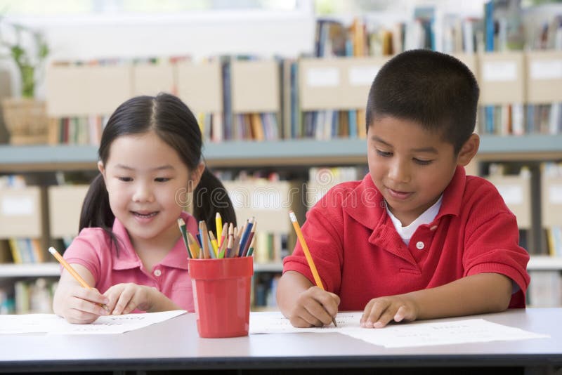 Children Sitting At Desk And Writing In Classroom Stock Photos - Image ...