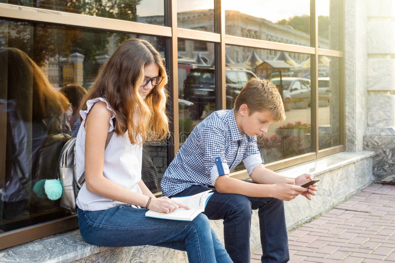 A Children Teenagers, Reading Book and Using Smartphone. Stock Photo ...
