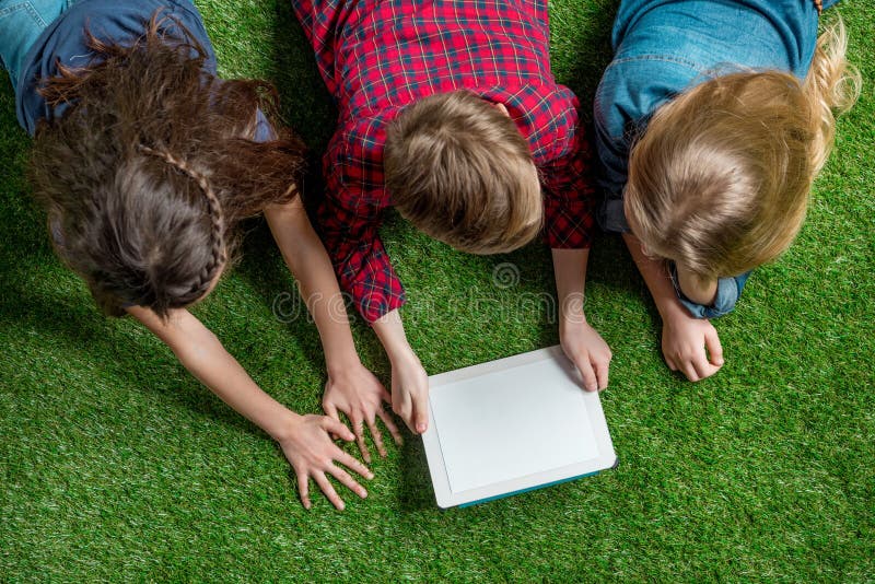 Children Using Digital Tablet while Lying on Grass Stock Photo - Image ...