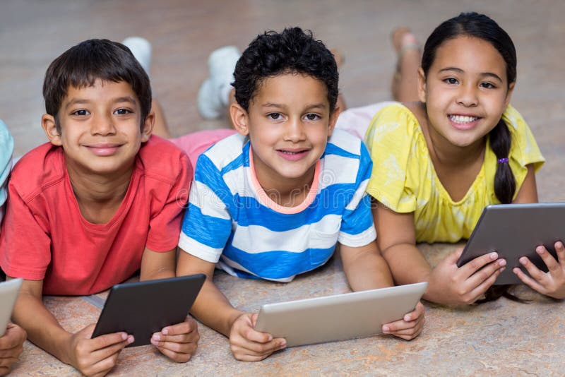 Children Using Digital Tablets while Lying on Floor Stock Image - Image ...