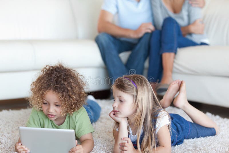 Children Using a Tablet Computer while Their Parents are Watching Stock ...