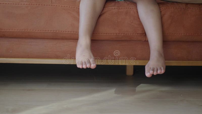 A Childs Tiny Feet Playfully Dangling from the Comfortable Sofa ...