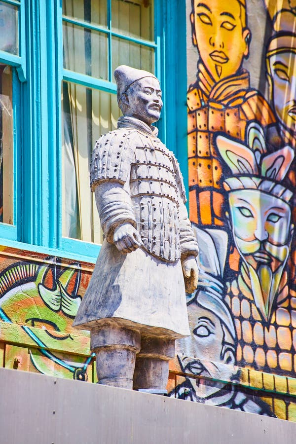 Statue of Chinese Man Standing in Front of Colorful Soldier Mural with ...