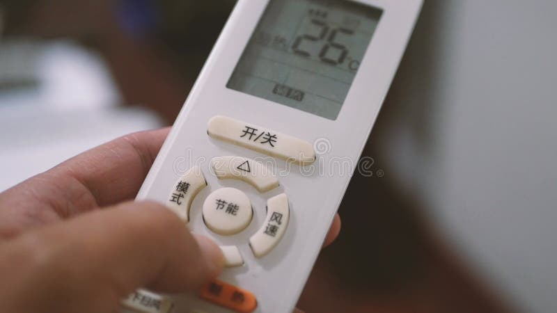 A Chinese is Using an Air Conditioner Remote Control To Adjust the ...