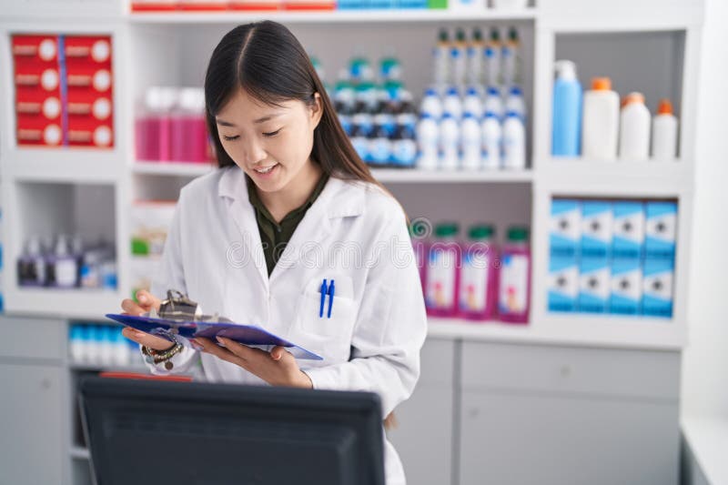 Chinese Woman Pharmacist Writing on Document at Pharmacy Stock Photo ...