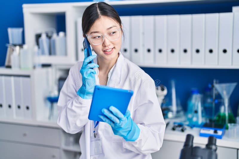 Chinese Woman Scientist Using Touchpad Talking on Smartphone at ...