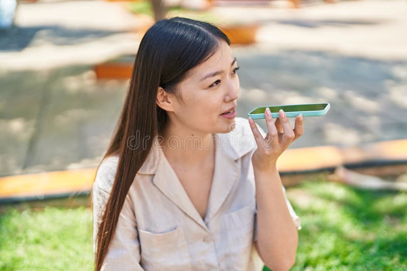 Chinese Woman Talking on the Smartphone Sitting on Grass at Park Stock ...