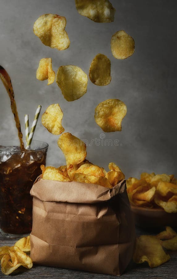Chips Falling into a Paper Bag with a Glass of Cola Being Poured Stock ...