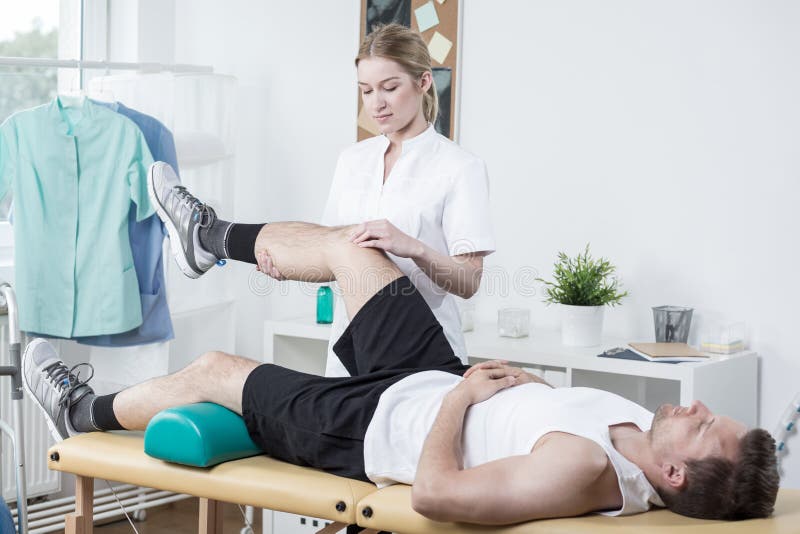 Chiropractor exercising man s leg. - Stock Image - Everypixel