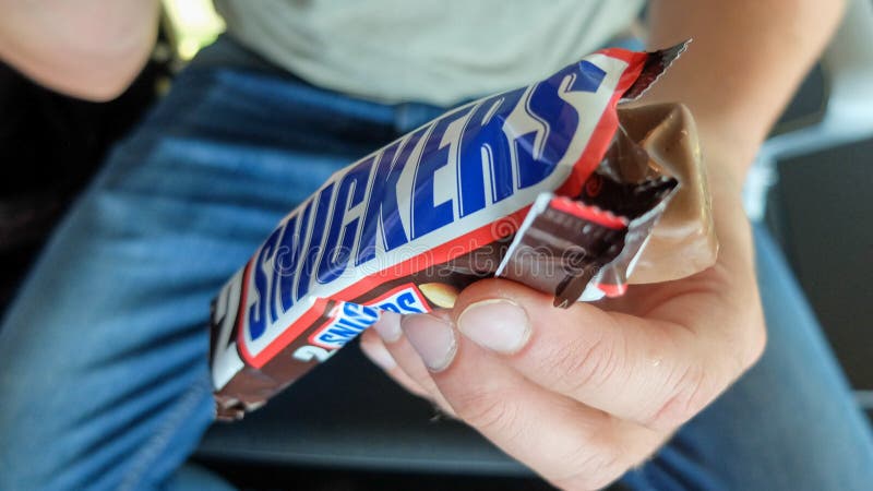 De Chocoladebar Van Snickers in De Bruine Verpakking Ligt Bij De Rode ...