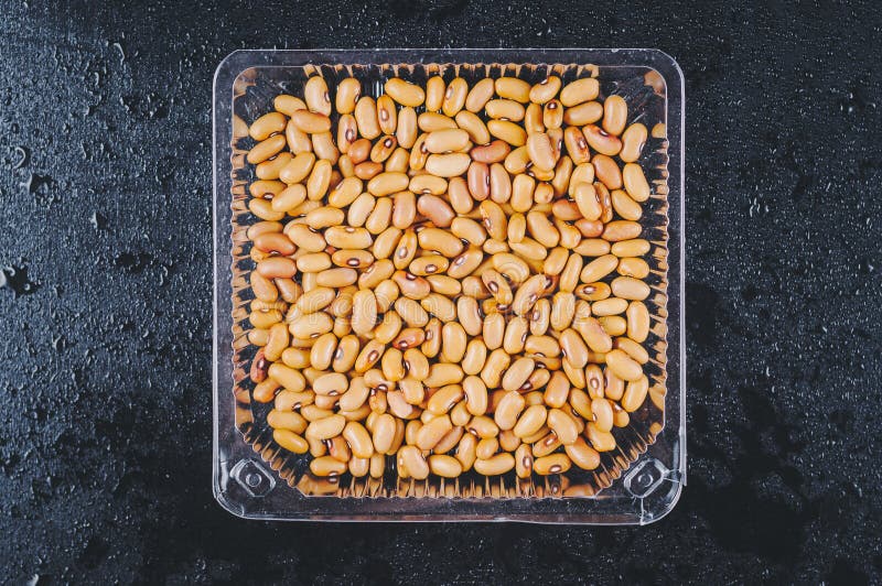 Chocolate Beans in a Plastic Container on a Dark Wet Surface Stock ...