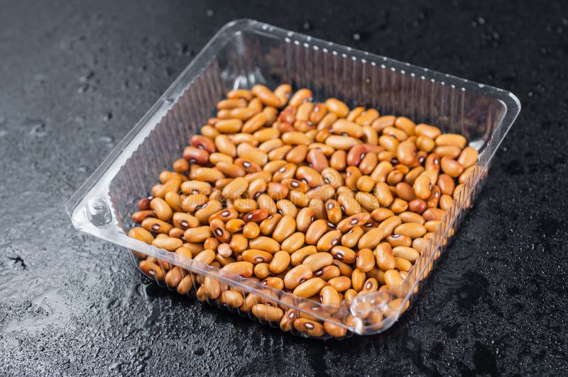 Chocolate Beans in a Plastic Container on a Dark Wet Surface Stock ...